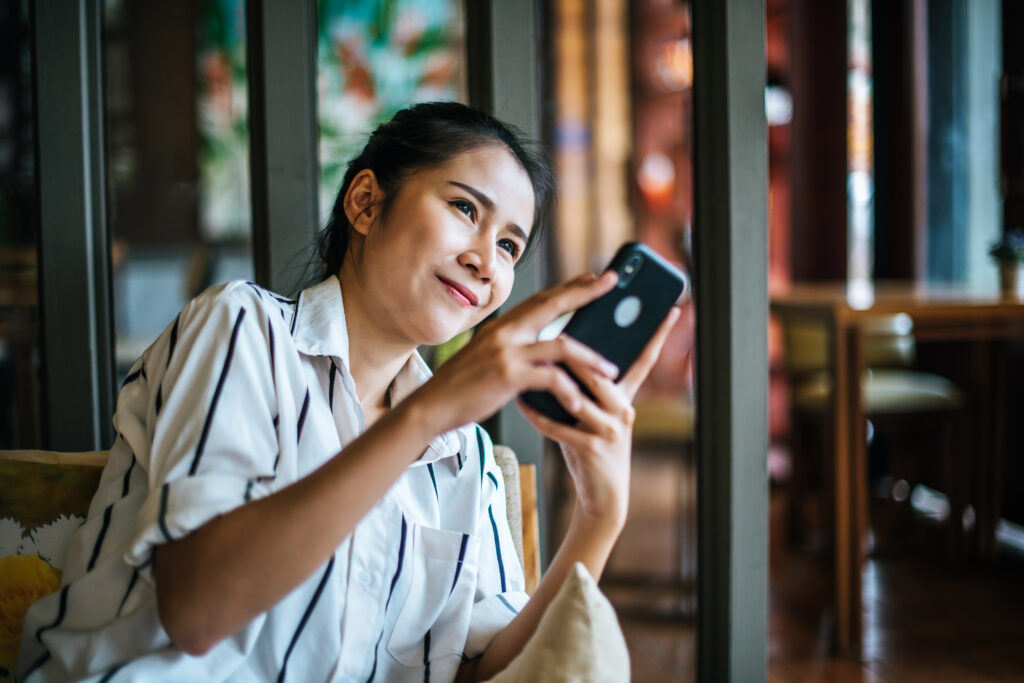 Woman Sitting and playing her smart phone at cafe | Microcontroller ...